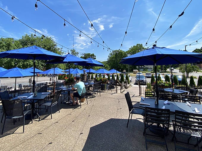 Summer dining perfection &ndash; blue umbrellas shade tables on the patio where string lights await evening's arrival to cast their magic.