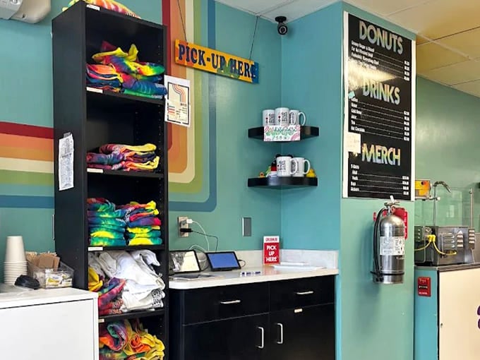 Colorful merchandise and a rainbow-striped wall create the perfect pick-up corner, extending the Peace, Love & Donuts experience beyond eating.