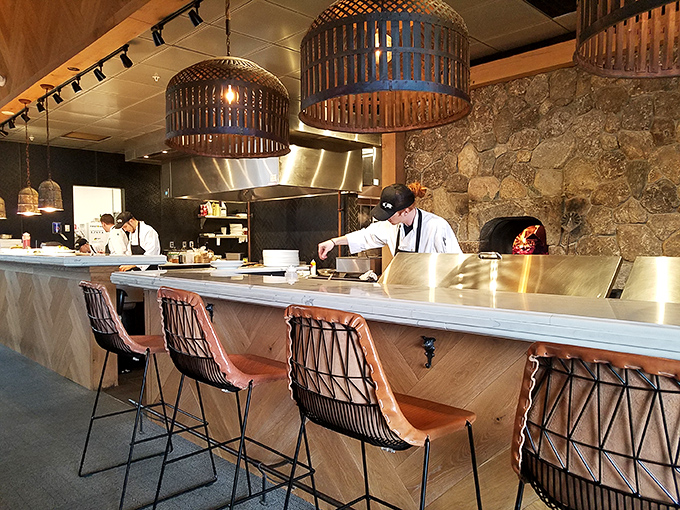 Counter seating offers a front-row view of culinary magic happening in the open kitchen, where flames dance and aromas tantalize.