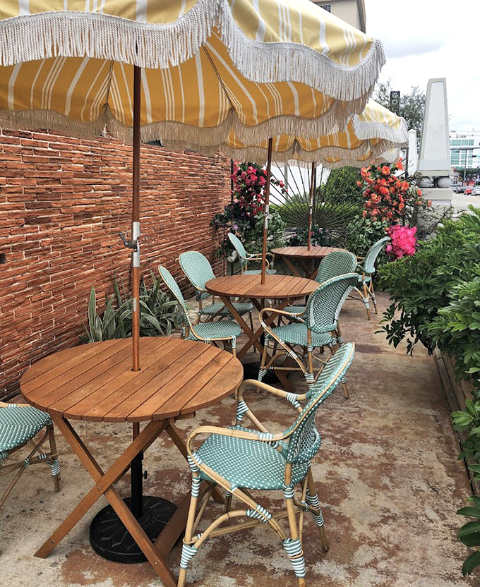 European caf&eacute; vibes with Florida sunshine &ndash; yellow-striped umbrellas shade mint-green chairs, creating the perfect setting for al fresco flavor adventures.