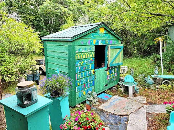 A whimsical green playhouse sits among colorful flowers at the Beaver Island Toy Museum, creating a magical backyard escape for the young at heart.