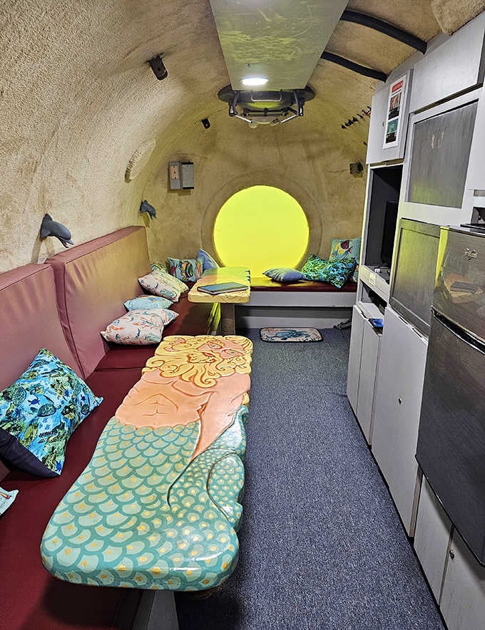 The submarine-like interior of Jules' Undersea Lodge features round portholes that glow with natural light, offering glimpses of marine life swimming by.