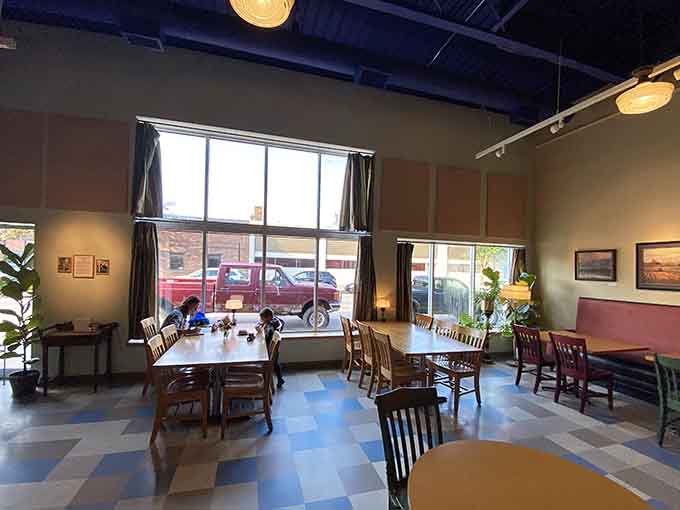 Sunlight streams through tall windows onto mismatched chairs and local art, creating the kind of welcoming space where time slows down and coffee tastes better.