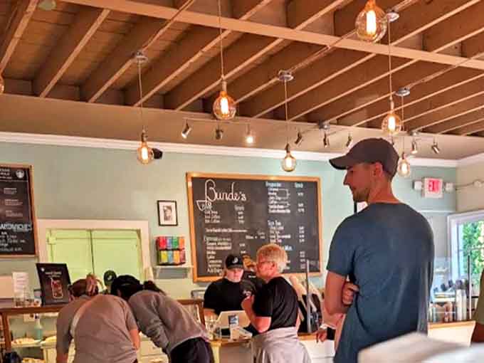 Edison bulbs cast a warm glow over eager customers waiting to experience pastry perfection in Bunde's welcoming interior.