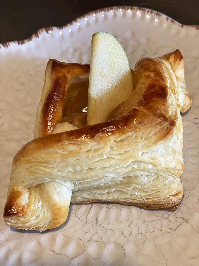 This isn't just any danish &ndash; it's a buttery revelation with a fresh apple slice peeking through, practically whispering "eat me" in pastry language.