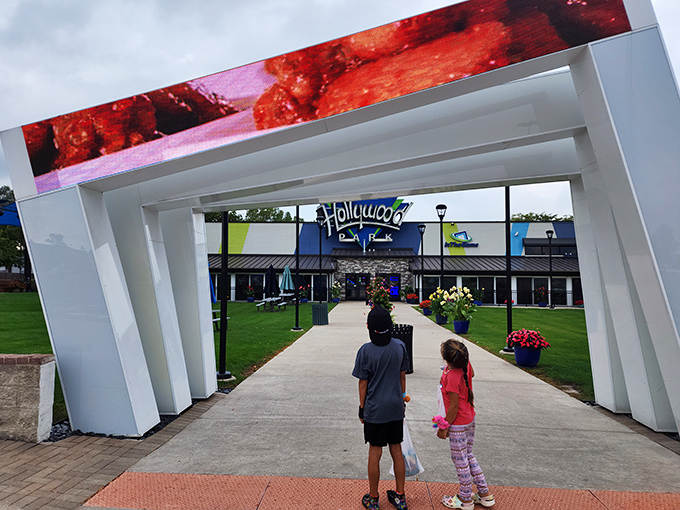 Children gaze in wonder at the impressive entrance portal, complete with a digital screen showcasing tempting treats that await inside.