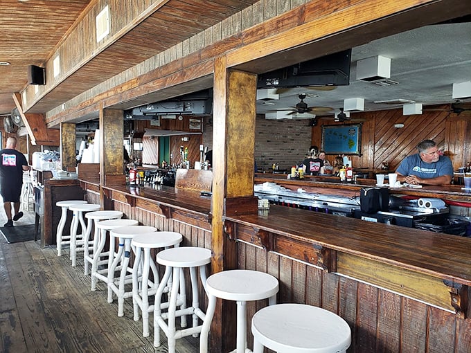 Weathered wood and white bar stools tell stories of countless beach days, while the rustic charm makes every hour feel like happy hour.