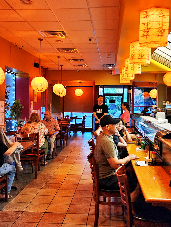 Warm amber lanterns cast a gentle glow across wooden tables and sushi bar, creating an atmosphere that whispers stay awhile.