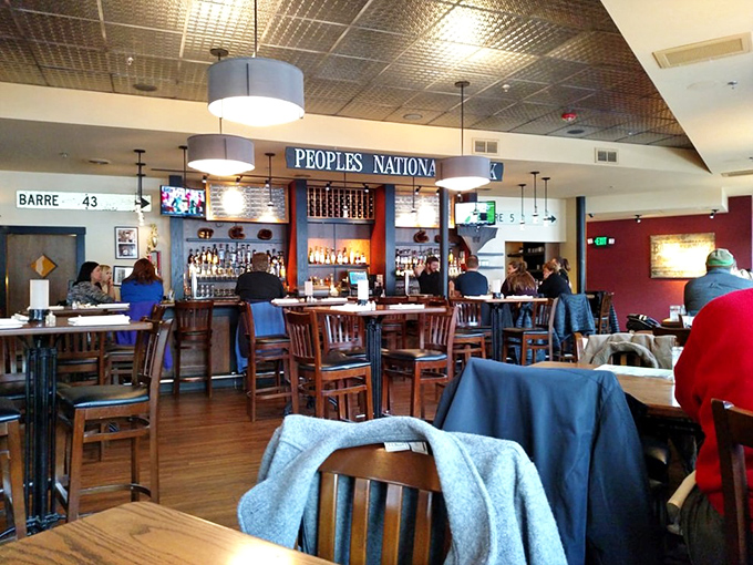 The bar area hums with conversation as patrons gather under the "Peoples National" sign, a nod to the building's banking history.