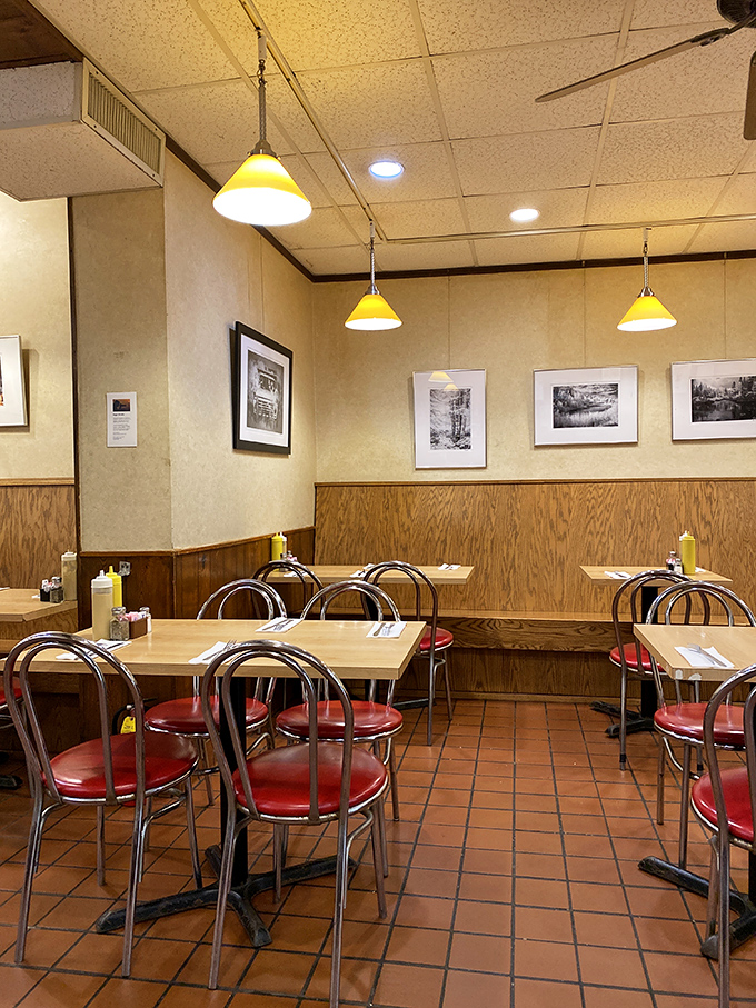 Step inside to discover the warm embrace of wood paneling, yellow pendant lights, and red vinyl chairs &ndash; comfort food for the soul before you even order.