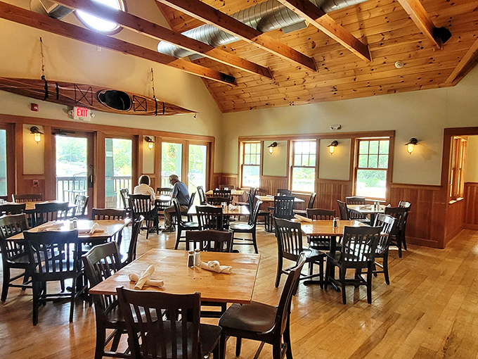 Warm wooden beams and natural light create a dining room that feels like Maine's coziest cabin, complete with a kayak suspended overhead.