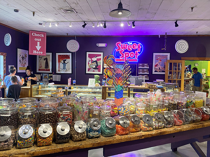 Step inside and behold candy paradise! Glass jars filled with colorful treats line wooden counters beneath purple walls and twinkling lights &ndash; childhood dreams realized.