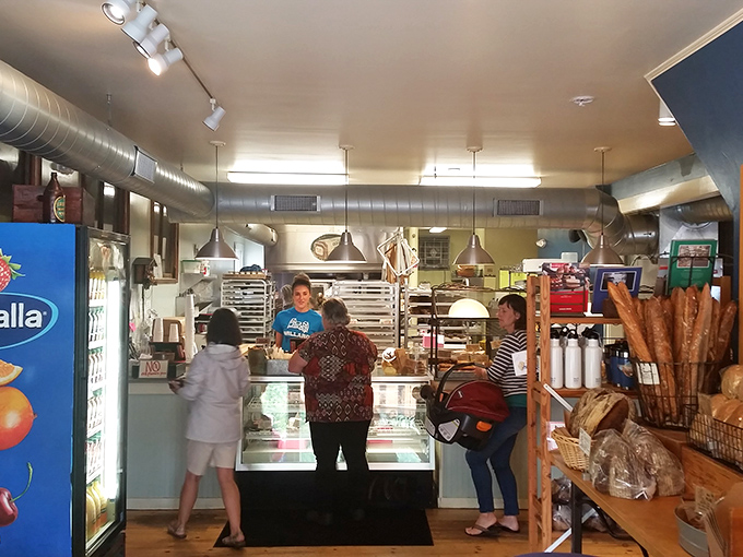 Inside, the bakery buzzes with anticipation as customers line up for their morning fix. The open kitchen concept lets you witness the magic happening.