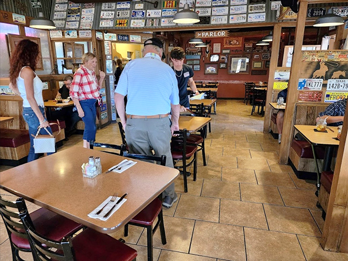 License plates from across America adorn the walls, creating a patchwork of road trip memories while diners enjoy hearty meals at wooden tables.