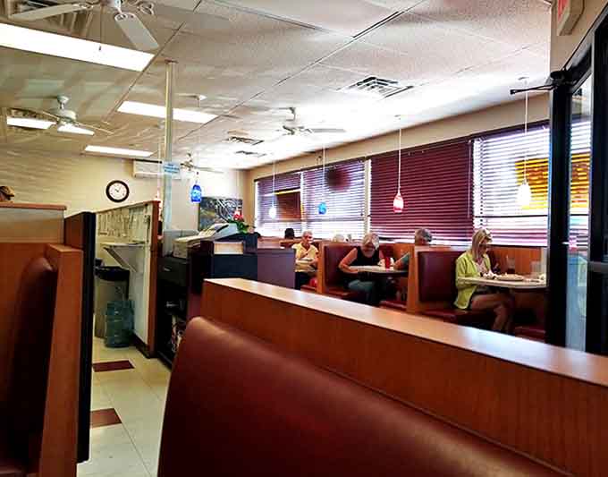Classic wooden booths with burgundy upholstery create that nostalgic diner atmosphere where conversations flow as freely as the coffee.