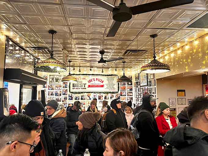 Inside Joe's, the bustling atmosphere and vintage ceiling create the perfect backdrop for pizza magic &ndash; notice the wall of fame documenting happy customers.