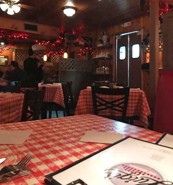 Inside Luigi's, warm wood paneling and twinkling lights create the perfect backdrop for memorable meals, while checkered tablecloths whisper of tradition.