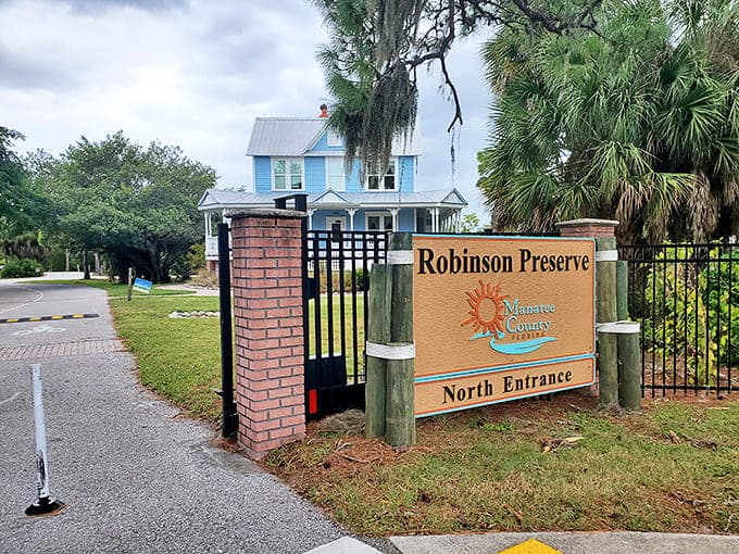 The North Entrance welcomes nature enthusiasts with a promise of adventure beyond the brick pillars and charming blue house backdrop.
