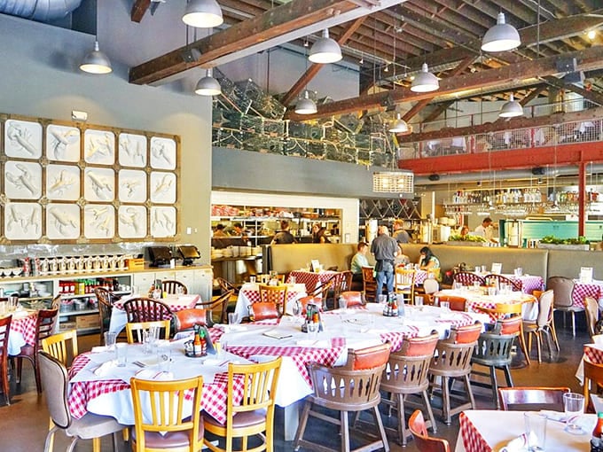 Soaring ceilings, exposed beams, and cheerful checkered tablecloths create an atmosphere that's equal parts industrial chic and backyard cookout.