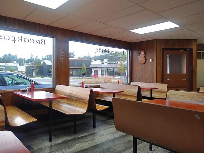Classic booth seating and wood paneling create that timeless diner atmosphere where comfort food feels right at home on orange tabletops.