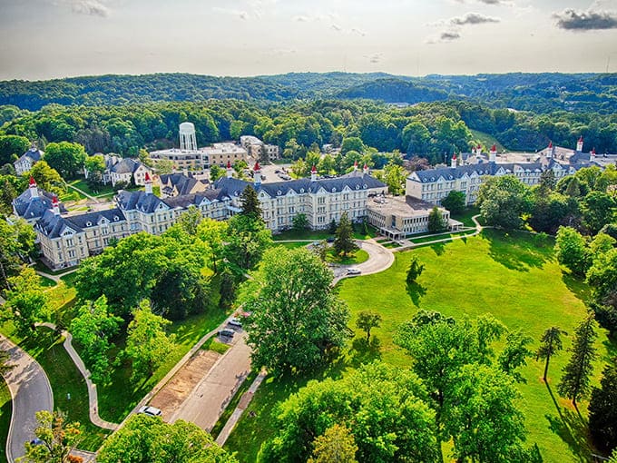 From above, the sprawling complex reveals its impressive scale, with distinctive red-capped towers punctuating the lush Michigan landscape like Victorian exclamation points.
