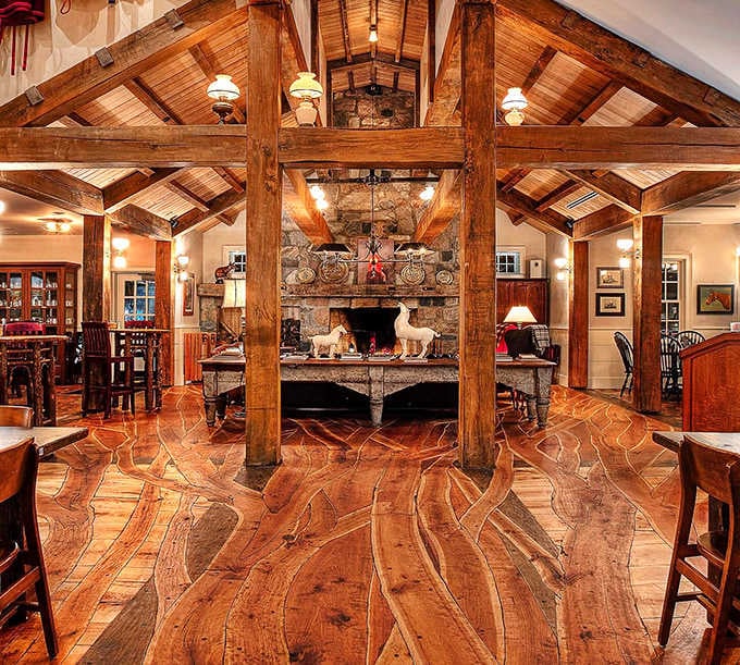 Rustic elegance defines the interior, where exposed wooden beams frame a magnificent stone fireplace that warms both the space and the soul.