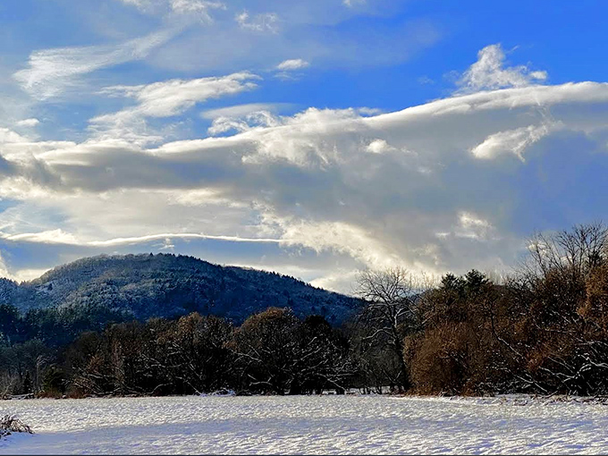 Winter transforms the landscape into a hushed wonderland, where snow-dusted mountains stand sentinel against a dramatic sky.