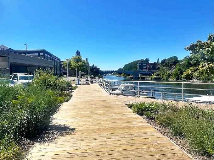 This sun-dappled wooden pathway beckons visitors forward, promising quiet moments and river views that change with every step taken.