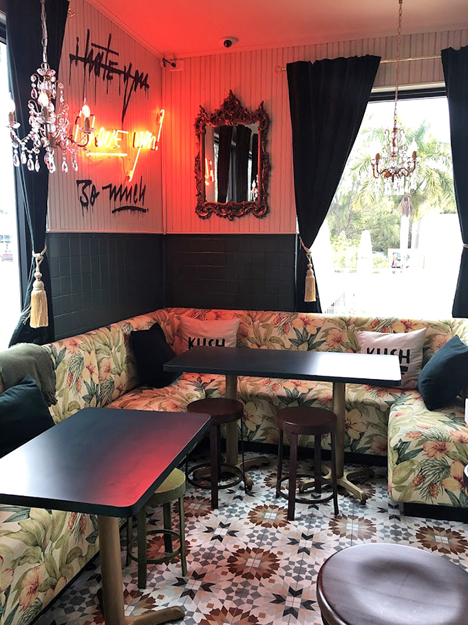 Neon dreams and floral fantasies collide in this cozy corner where "I hate you so much" glows with ironic warmth against vintage-inspired banquettes.
