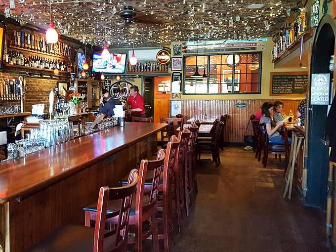 Inside, the ceiling sparkles with dollar bills and business cards, creating a glittering canopy above the warm wooden bar.