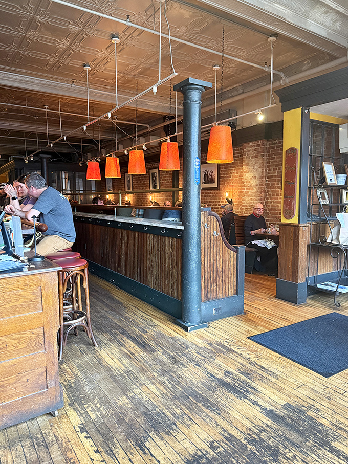 Warm orange pendant lights hang from pressed tin ceilings, while exposed brick and wooden accents create that "where everybody knows your name" atmosphere.