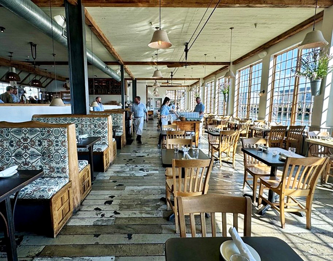 Sunlight streams through massive windows, illuminating a dining room where rustic charm meets waterfront elegance without a hint of pretension.