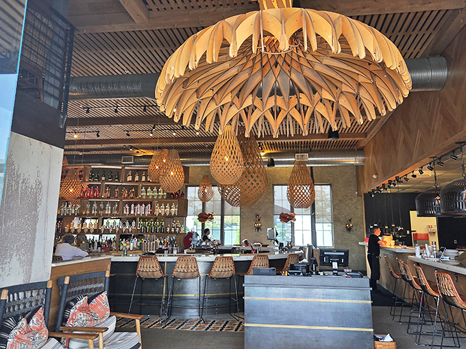 The dramatic interior features stunning wooden pendant lights that cast a warm glow over the bar area, creating an atmosphere that's both modern and inviting.