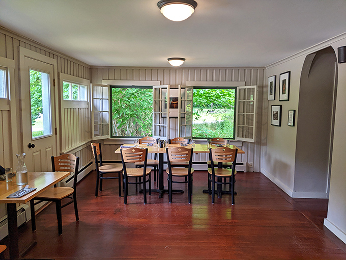 Sunlight streams through windows in this cozy dining space, where simple wooden tables invite guests to settle in for a memorable meal.