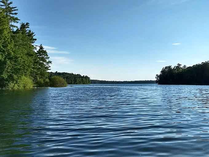 Morning mist dances across the surface as sunlight filters through towering pines, creating nature's own light show.
