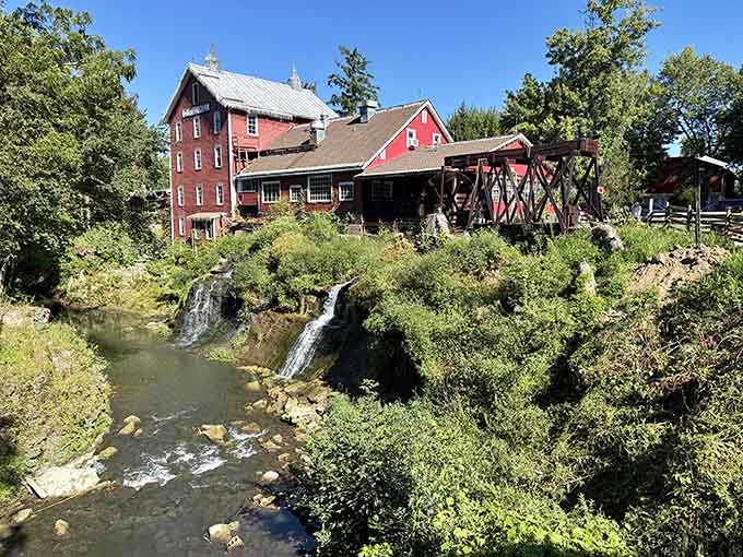 The mill's weathered red exterior and surrounding greenery create a scene so perfect you'll swear someone staged it, but Mother Nature doesn't need a stylist.