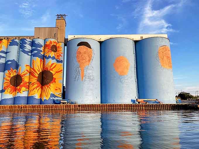 A work in progress reveals the artistic journey, with outlined figures waiting to bloom into full color on the massive grain silos.
