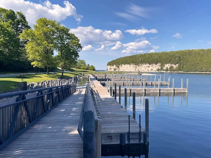 A wooden bridge stretches across calm waters, inviting visitors to cross between present day and a bygone industrial era.