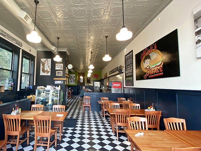Classic black and white checkered floors meet warm wooden tables under a vintage pressed tin ceiling &ndash; diner perfection that feels both nostalgic and timeless.
