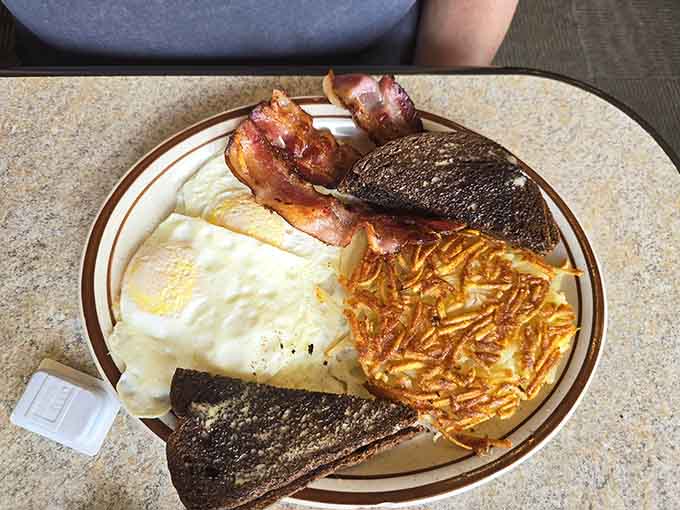This is what breakfast dreams are made of: perfectly cooked eggs, crispy bacon, golden hash browns, and toast ready for action.