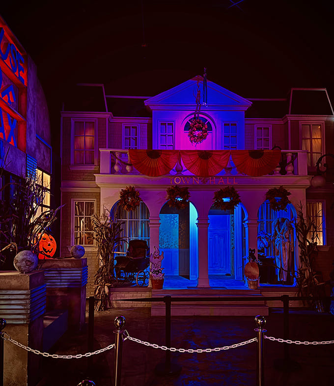 The Town Hall stands as a centerpiece of horror, its classic architecture and festive orange bunting creating a false sense of normalcy before the scares begin.