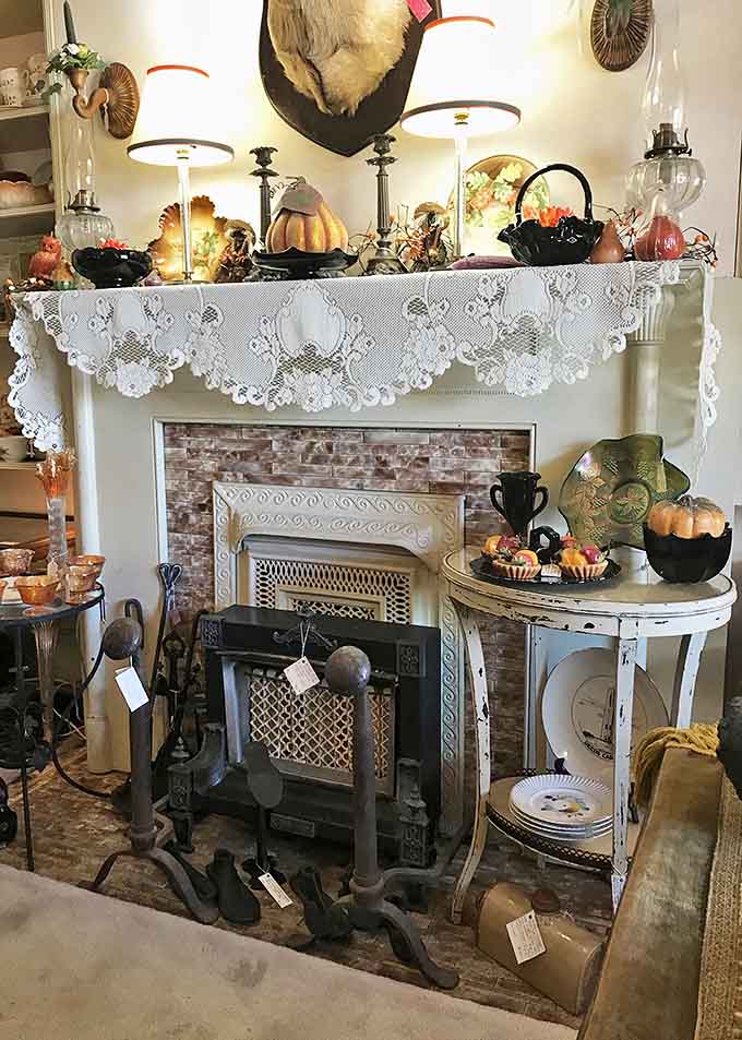 A carefully arranged mantelpiece showcases the shop's eclectic treasures, from vintage lamps to seasonal decorations.