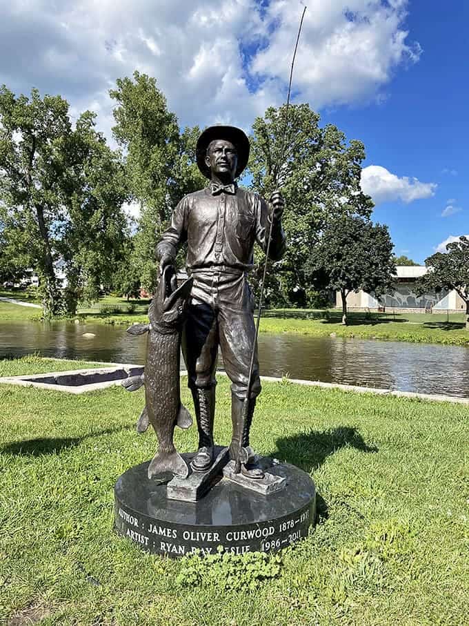 A bronze fisherman forever casts his line into history &ndash; James Oliver Curwood immortalized beside the river that inspired his wilderness adventures.