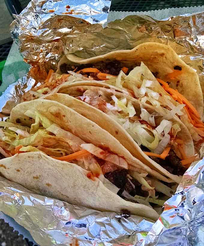 Beef tacos wrapped in foil like edible presents, each one hiding layers of perfectly seasoned deliciousness inside.