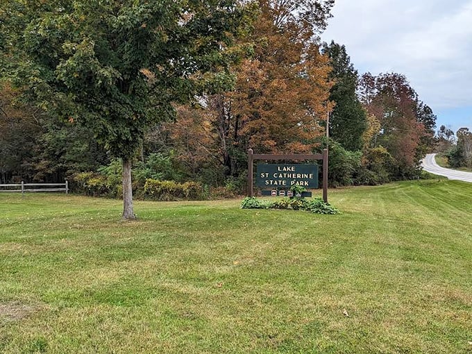 The welcoming committee: Lake St. Catherine's rustic sign stands amid autumn foliage, promising adventures beyond the ordinary.