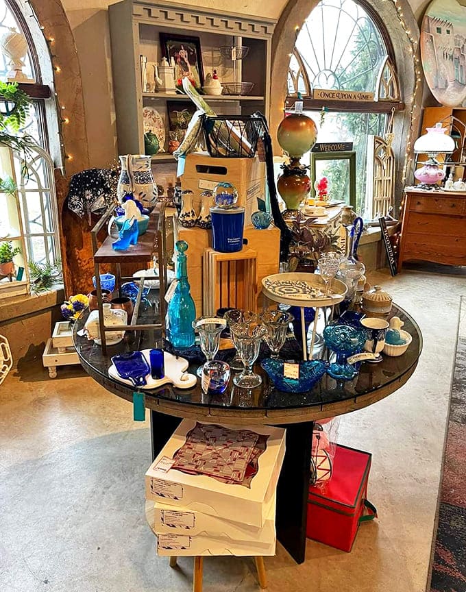 Sunlight streams through arched windows, illuminating blue glassware that transforms ordinary light into pools of sapphire magic on wooden shelves.