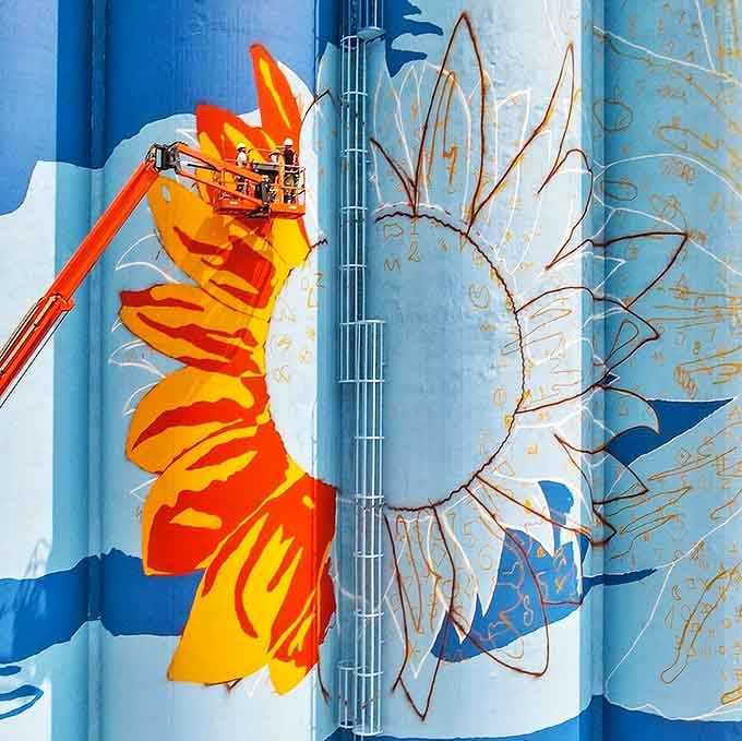 Each sunflower petal is meticulously painted on the curved concrete surface, creating a three-dimensional effect that seems to follow you.