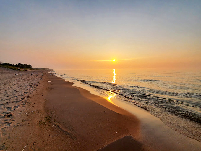Waves crash against a shore backed by towering dunes. It's like the Sahara met the Great Lakes!