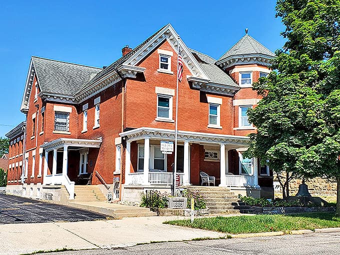 The stately red brick Victorian mansion of the Allegan County Historical Society stands proudly against a blue sky, preserving history in architectural splendor.