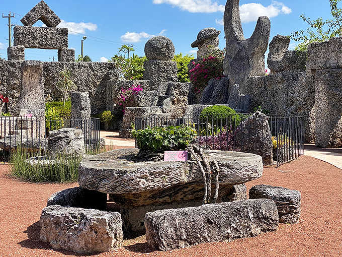 Coral Castle's stone garden showcases perfectly balanced megalithic sculptures, with flowering plants adding color to the otherwise monolithic landscape.